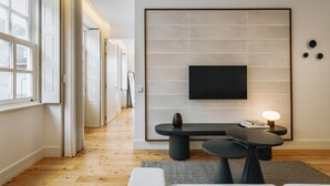 Uma sala de estar moderna com uma TV de tela plana na parede, uma mesa de centro escura e um sofá.