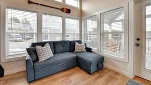 Uma sala de estar moderna com um sofá seccional cinza, almofadas estampadas e uma decoração de parede com um remo de madeira.