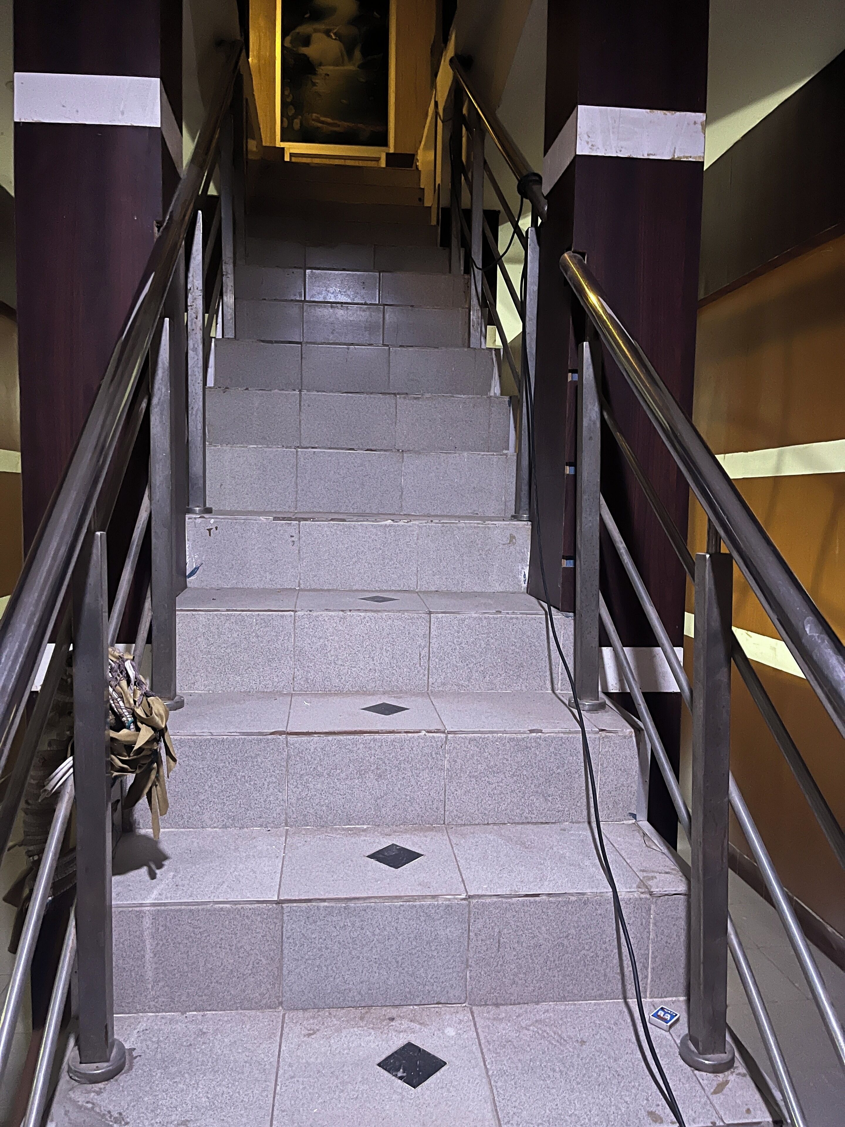 Escadaria com grades de metal e degraus azulejados, que leva a um andar superior.