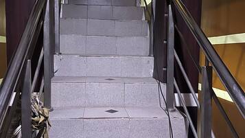 Escadaria com grades de metal e degraus azulejados, que leva a um andar superior.