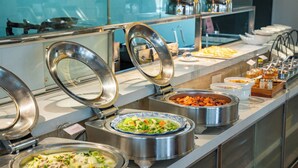 Buffet com diversos alimentos em recipientes metálicos, incluindo saladas e sopas.
