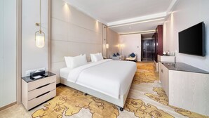 Quarto de hotel moderno com uma cama grande, mesas de cabeceira, escrivaninha e televisão de tela plana.