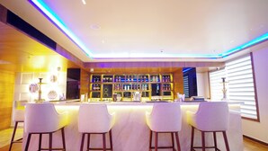Uma área de bar moderna com balcão de madeira, vários bancos e interior bem iluminado.