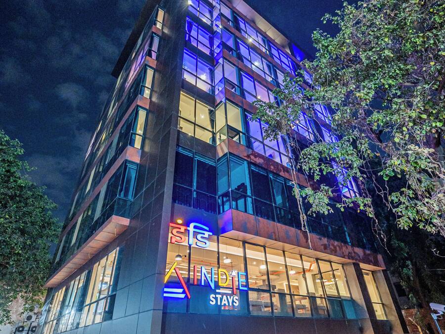Um edifício moderno com fachada de vidro, letreiros iluminados e área de entrada bem iluminada.