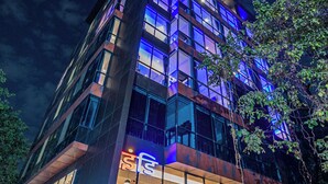 Um hotel moderno com fachada de vidro e sinalização iluminada.
