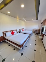 Quarto de hotel com duas camas, um ventilador de teto e uma televisão.