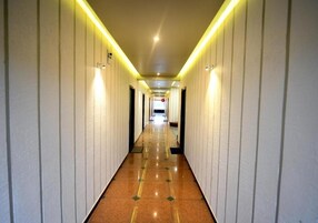 Um corredor comprido e estreito com piso brilhante e reflexivo, e paredes brancas.