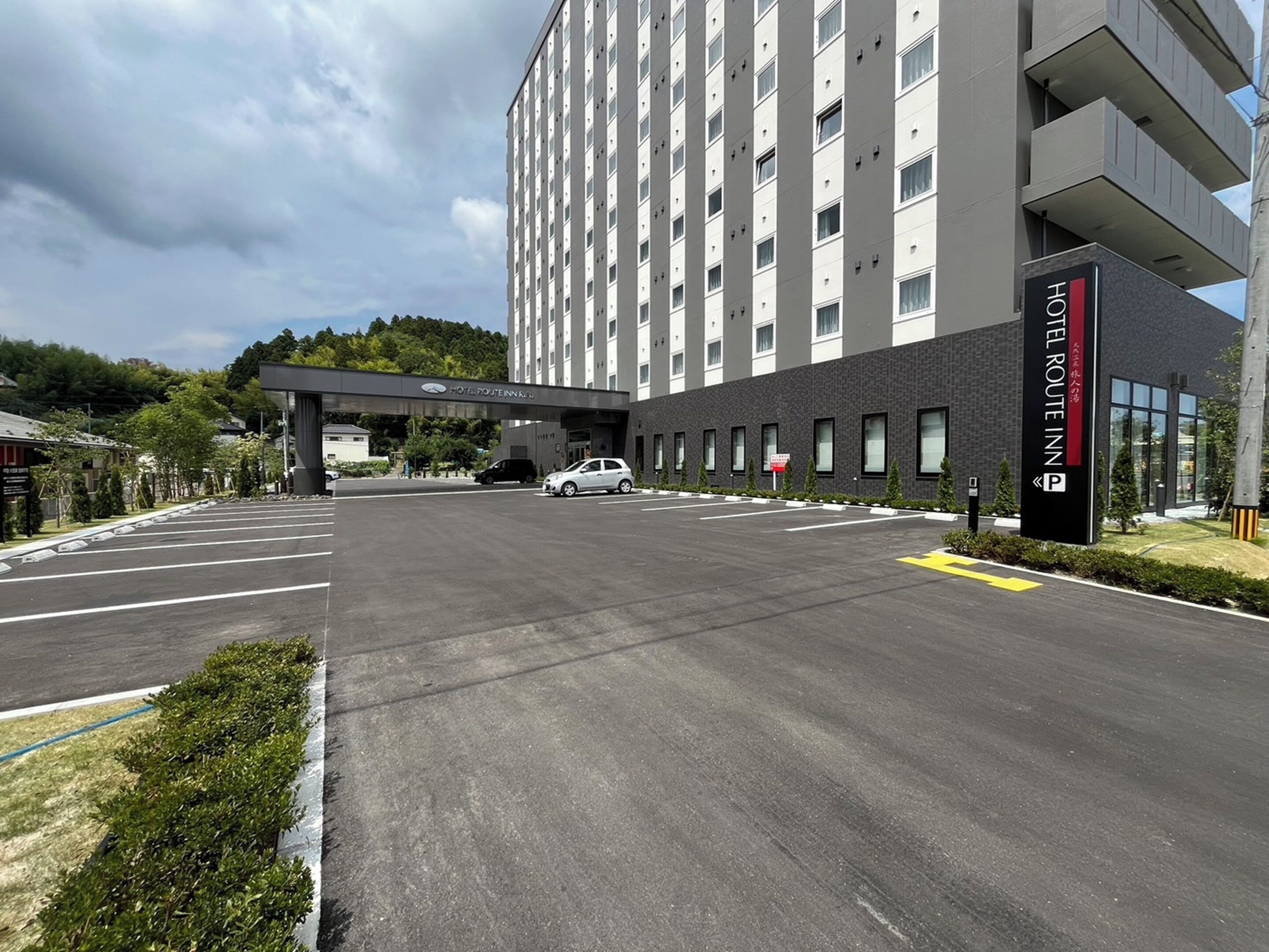 Entrada moderna de um hotel com estacionamento, uma cobertura e a placa Hotel Route Inn.