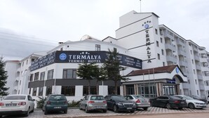 Um hotel com uma placa indicando "Termalya Hotel" e comodidades listadas, incluindo spa, sauna e parque aquático.