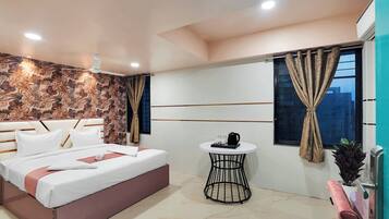 Quarto moderno com cama, uma mesinha redonda e janela com cortinas.