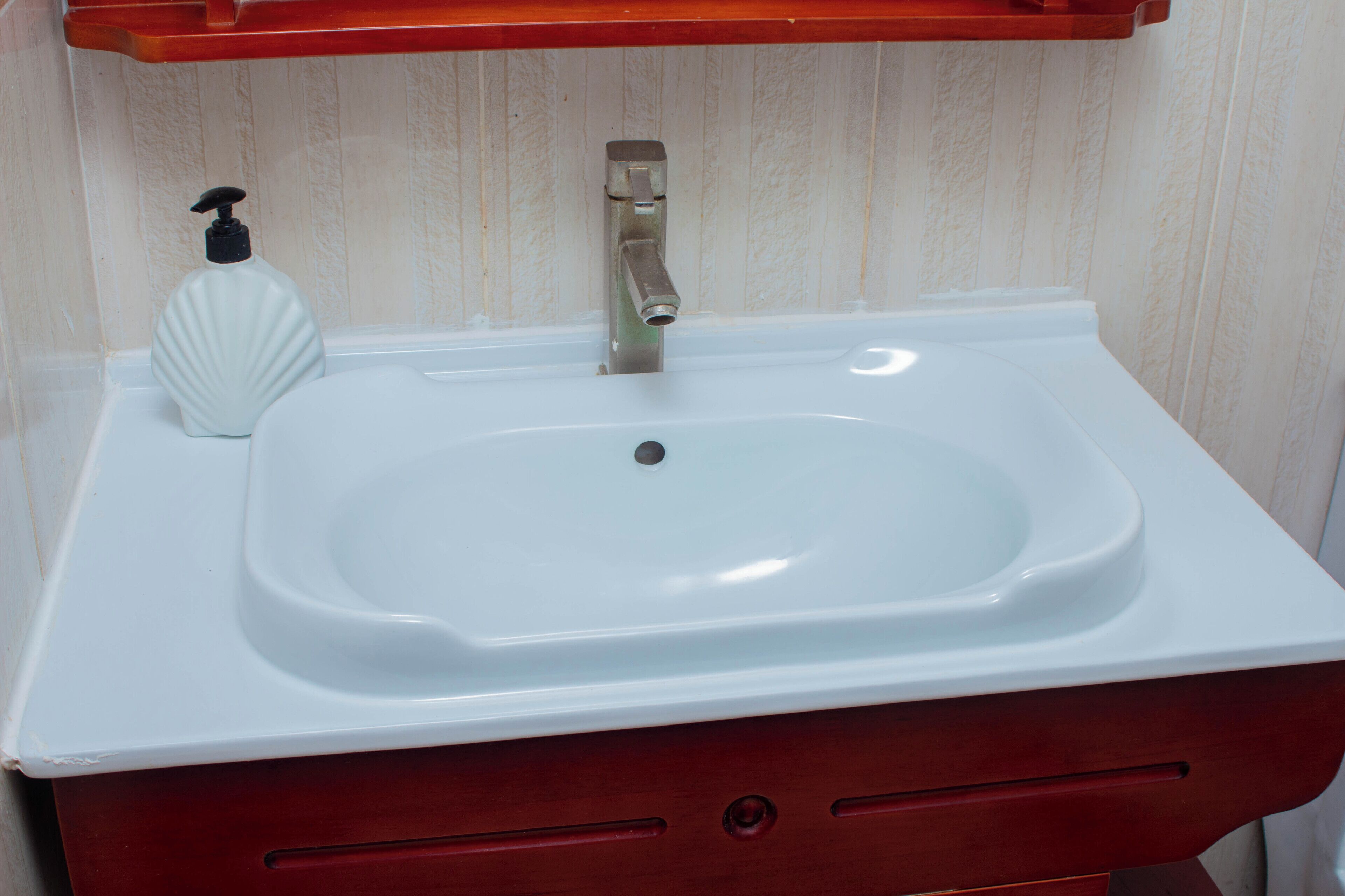 Casa de banho com uma pia branca, toucador vermelho e dispensador de sabonete.