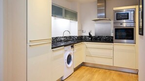 Uma cozinha moderna com máquina de lavar, micro-ondas e forno embutido.
