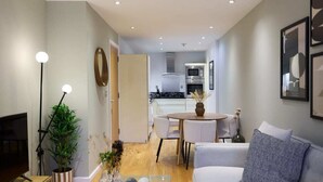 Uma sala de estar moderna com televisão de tela plana, sofá e área de refeições com mesa e cadeiras.