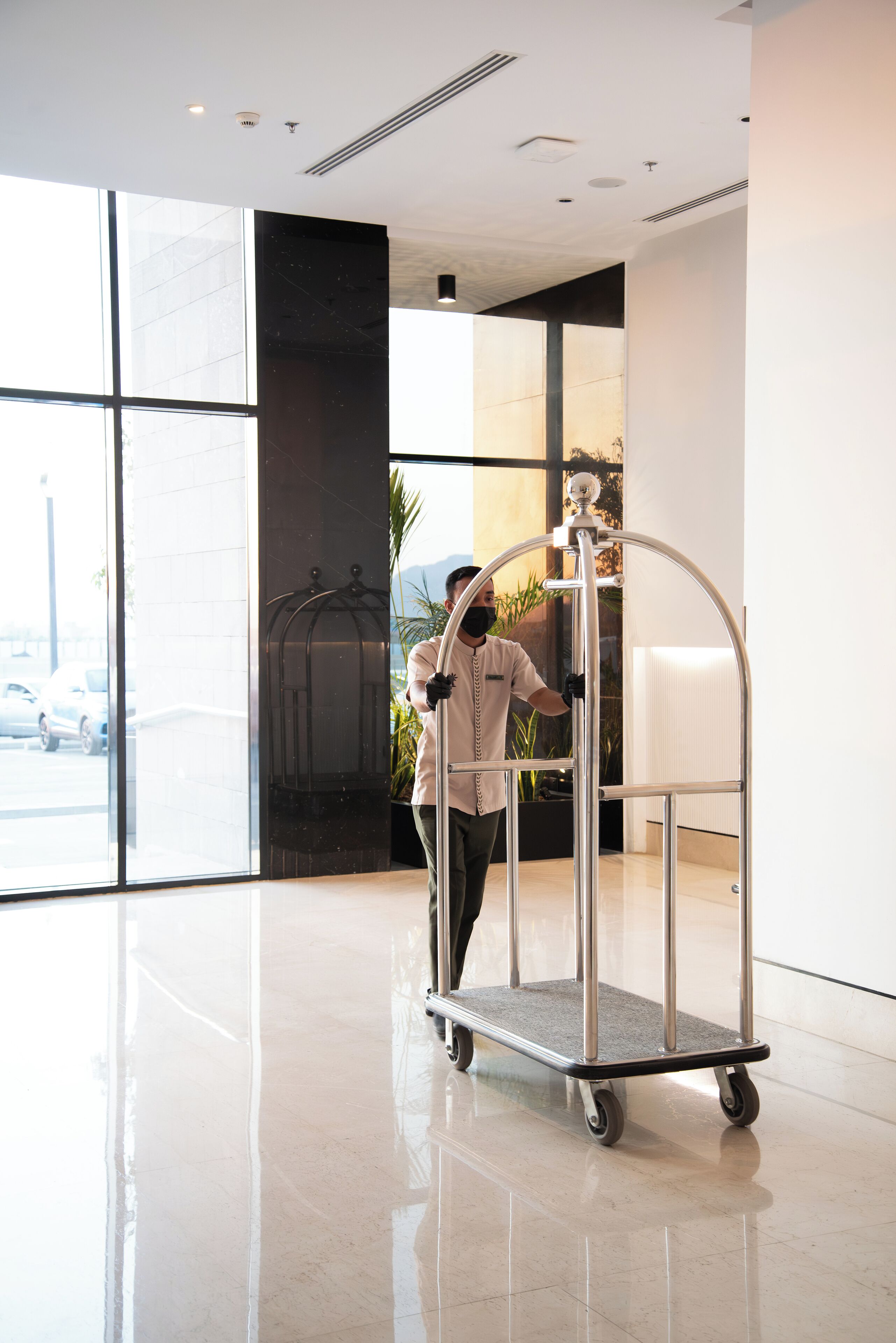 Um saguão de hotel com uma grande janela de vidro, uma mesa de recepção e um elevador moderno.