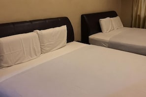 Duas camas de solteiro com cabeceiras pretas e roupa de cama branca em um quarto de hotel.