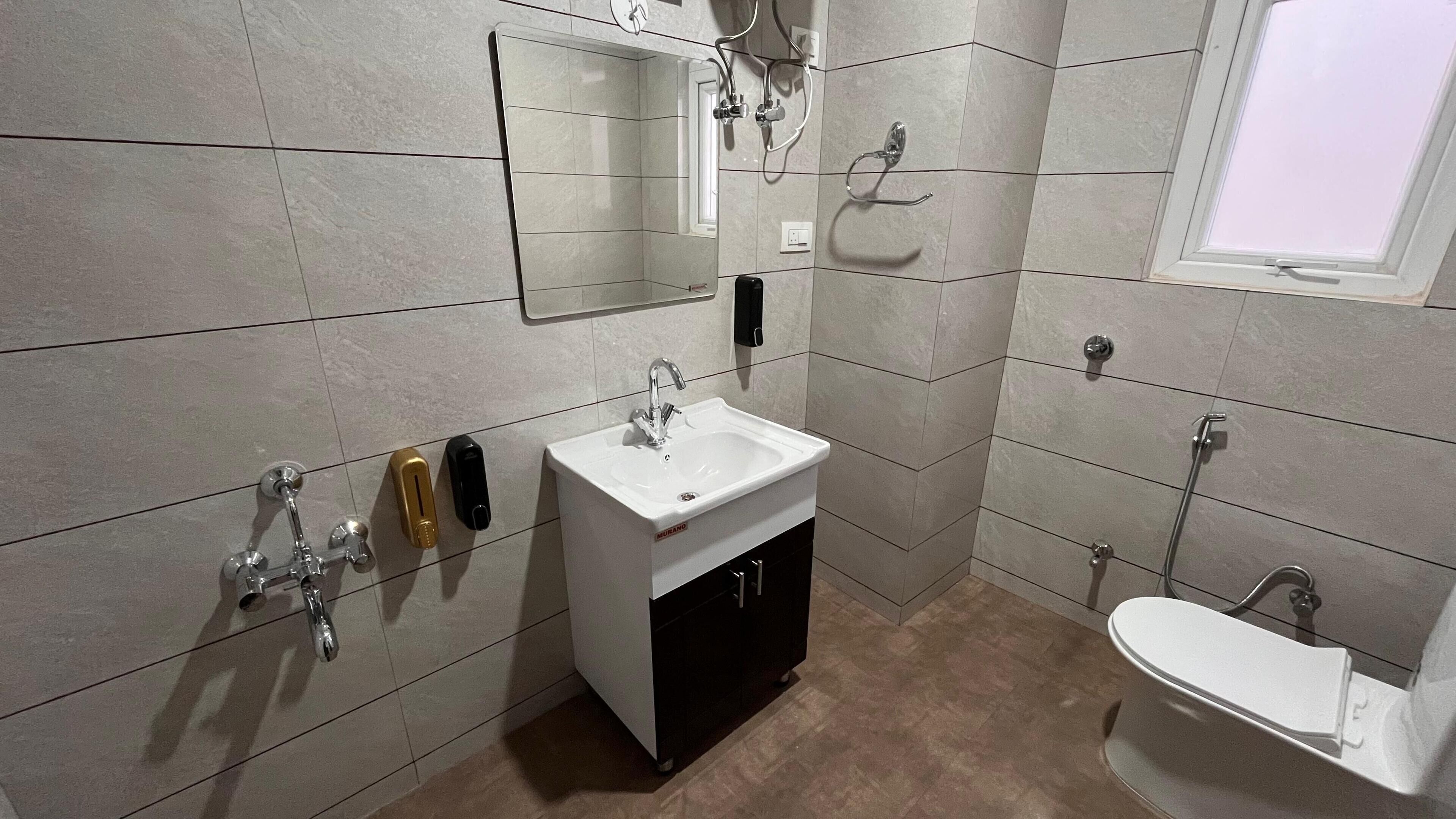 Casa de banho com lavatório branco, sanita e zona de duche.