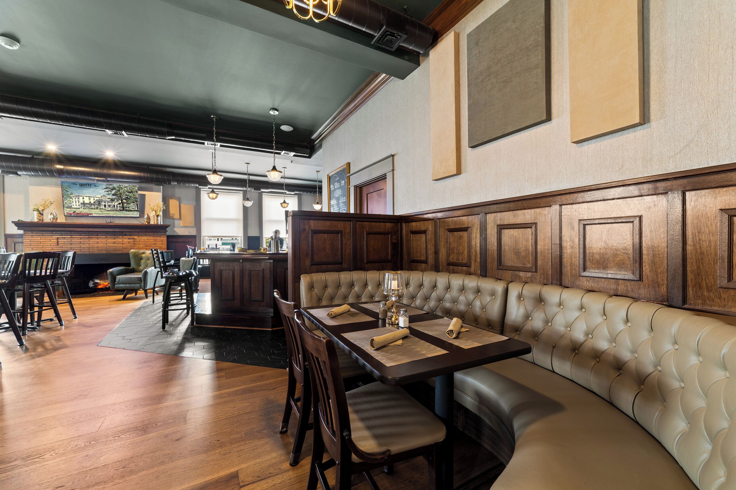 Interior de restaurante com área de cabines, mesas e cadeiras de madeira.