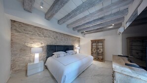 Quarto com uma cama grande, parede de pedra e teto de madeira.