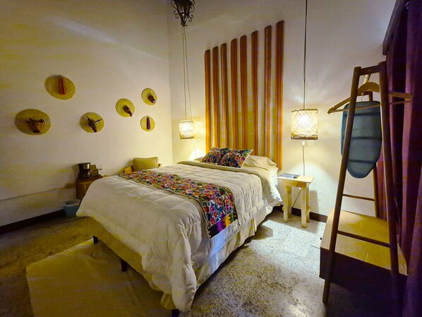Um quarto com cama, mesas de cabeceira, luminária pendente, prateleira na parede e escada.