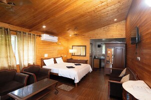 Quarto estilo cabana de madeira com cama, dois sofás, mesa e televisão.