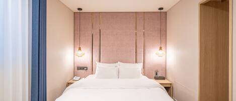 Quarto de hotel moderno com uma cama grande, duas mesas de cabeceira e um guarda-roupa de madeira.