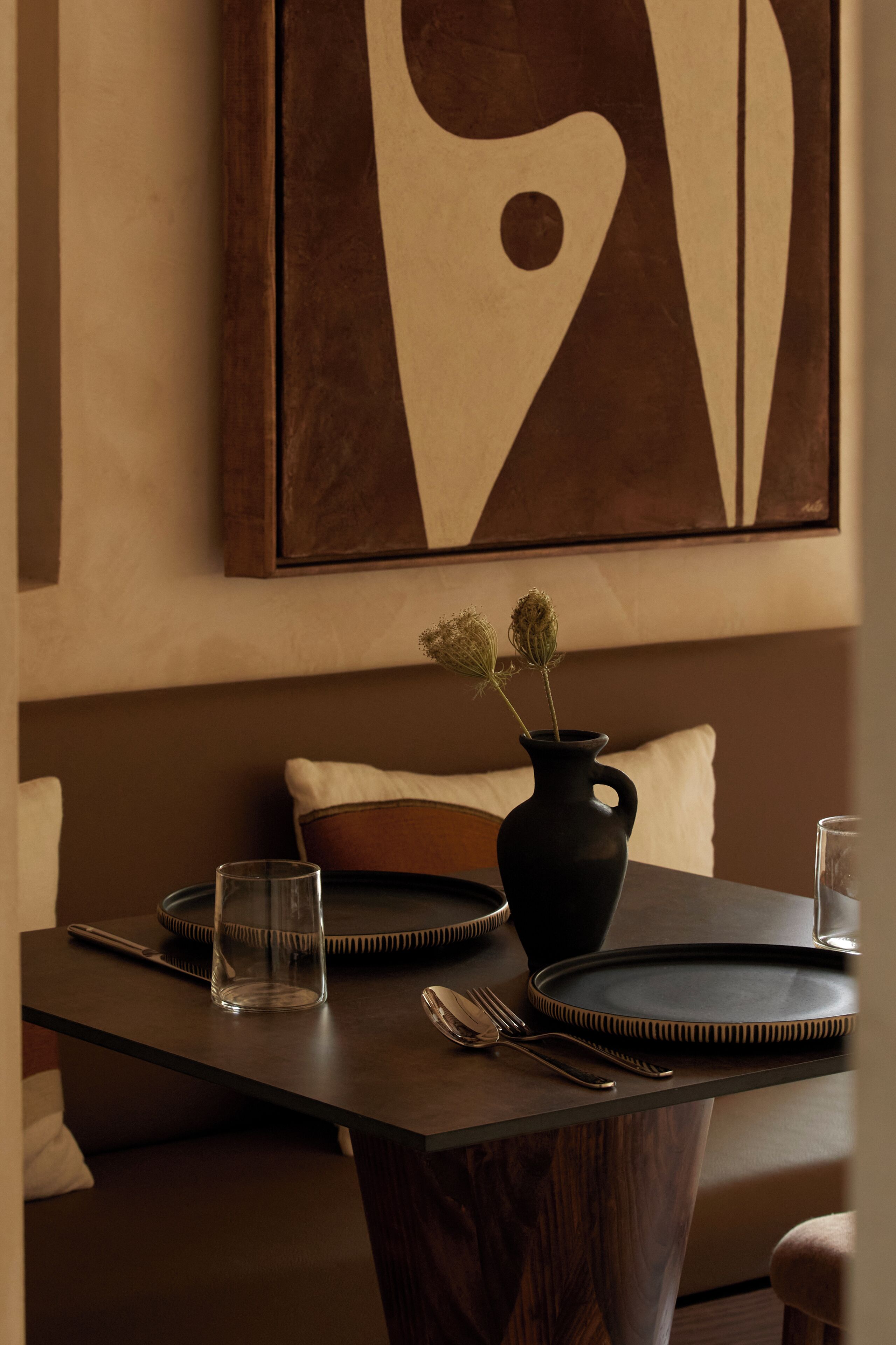 Uma mesa de jantar com pratos, talheres e um vaso com flores.