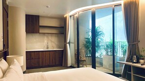 Quarto de hotel moderno com cama, banheiro com pia e varanda com plantas.