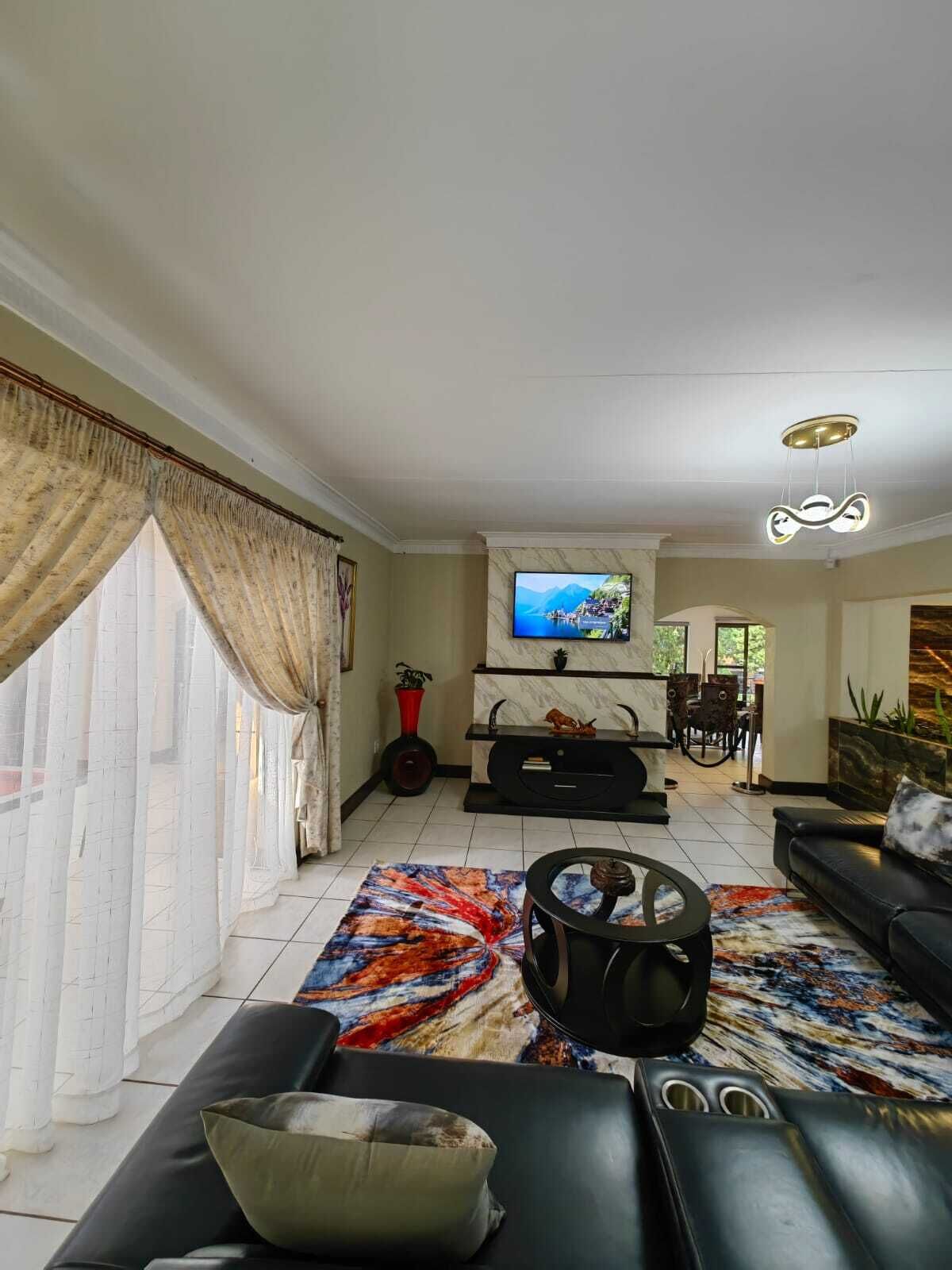 Uma sala de estar moderna com televisão de tela plana, sofá de couro preto e um tapete colorido.