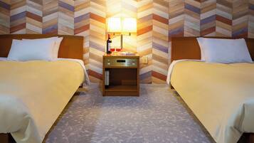 Quarto de hotel com duas camas, uma mesa de cabeceira com abajur e parede estampada.