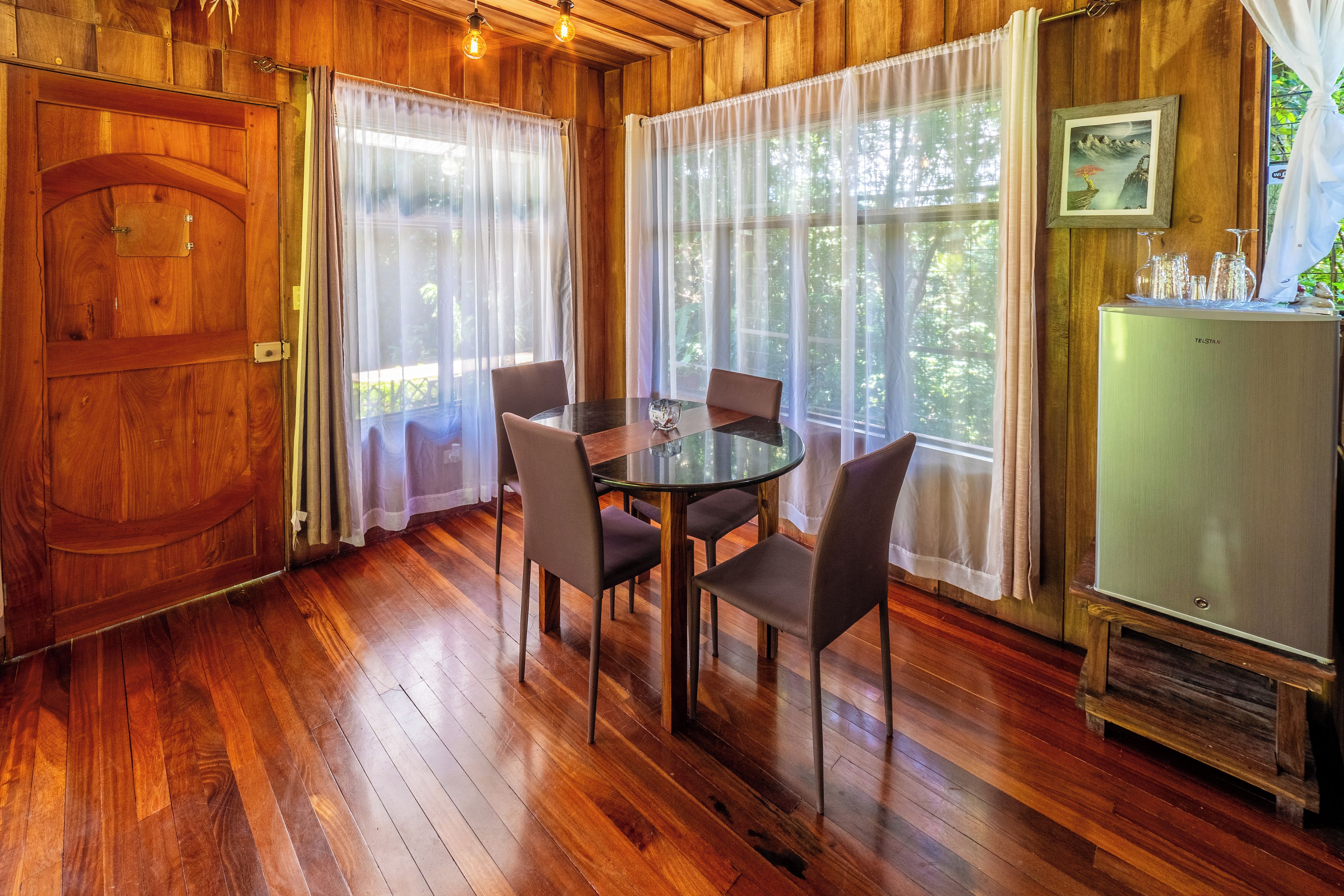 Interior de madeira com uma mesa de jantar, cadeiras e uma geladeira.
