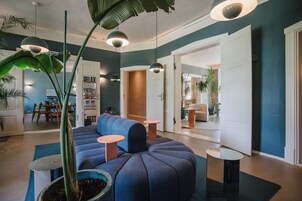 Uma sala de estar moderna com um sofá azul, mesas redondas e luminárias pendentes.