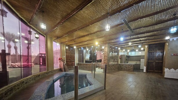 Amplo espaço interno com piscina, piso de madeira e teto alto com vigas aparentes.