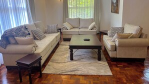 Uma sala de estar com sofá seccional, mesa de centro e tapete estampado.