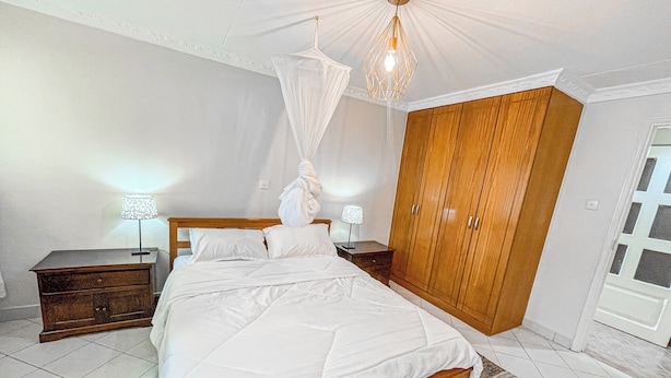 Quarto com cama de madeira, mesa de cabeceira, guarda-roupa e luminária pendente.