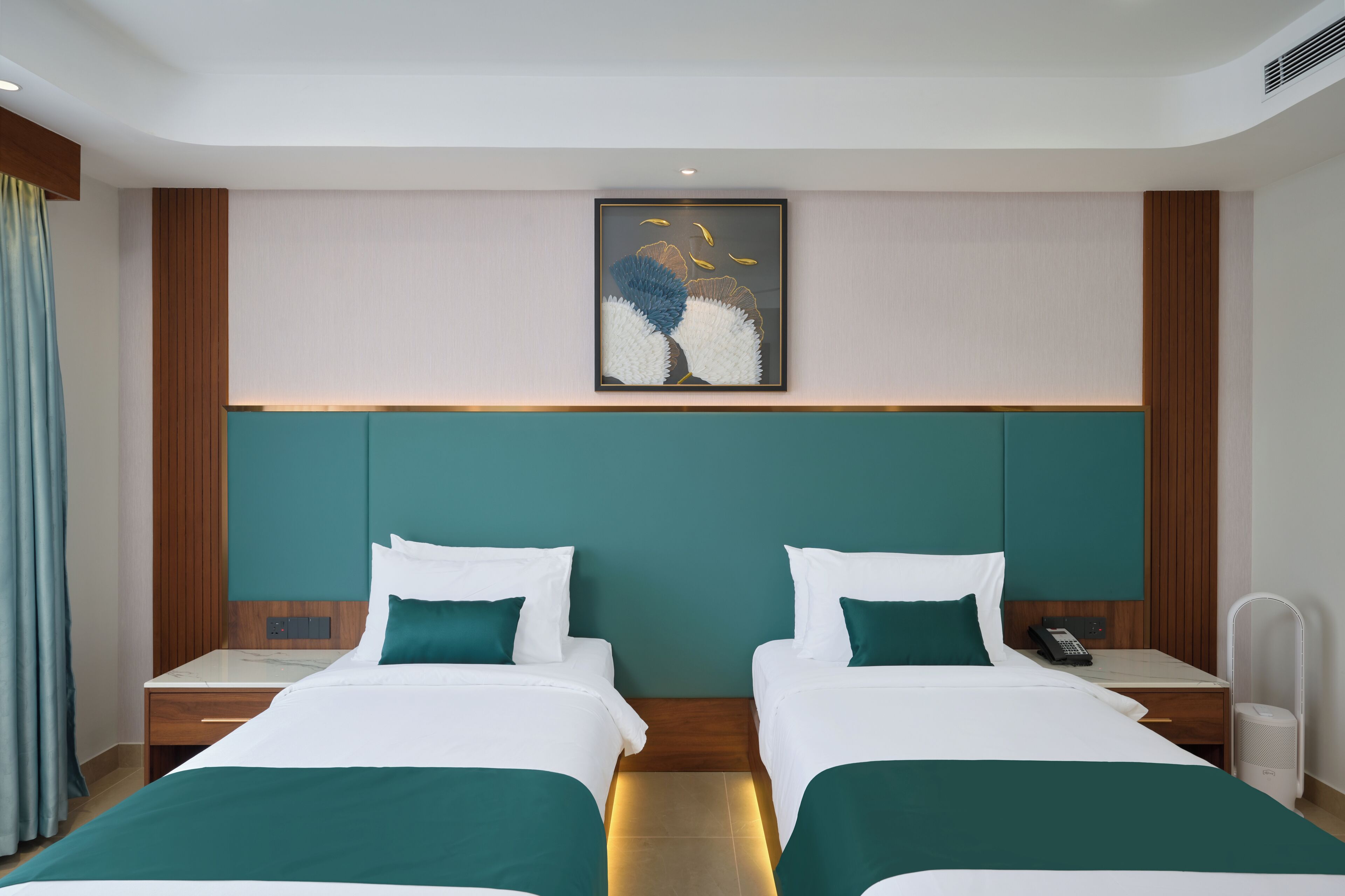 Quarto de hotel com duas camas, um quadro na parede e um telefone na mesinha de cabeceira.