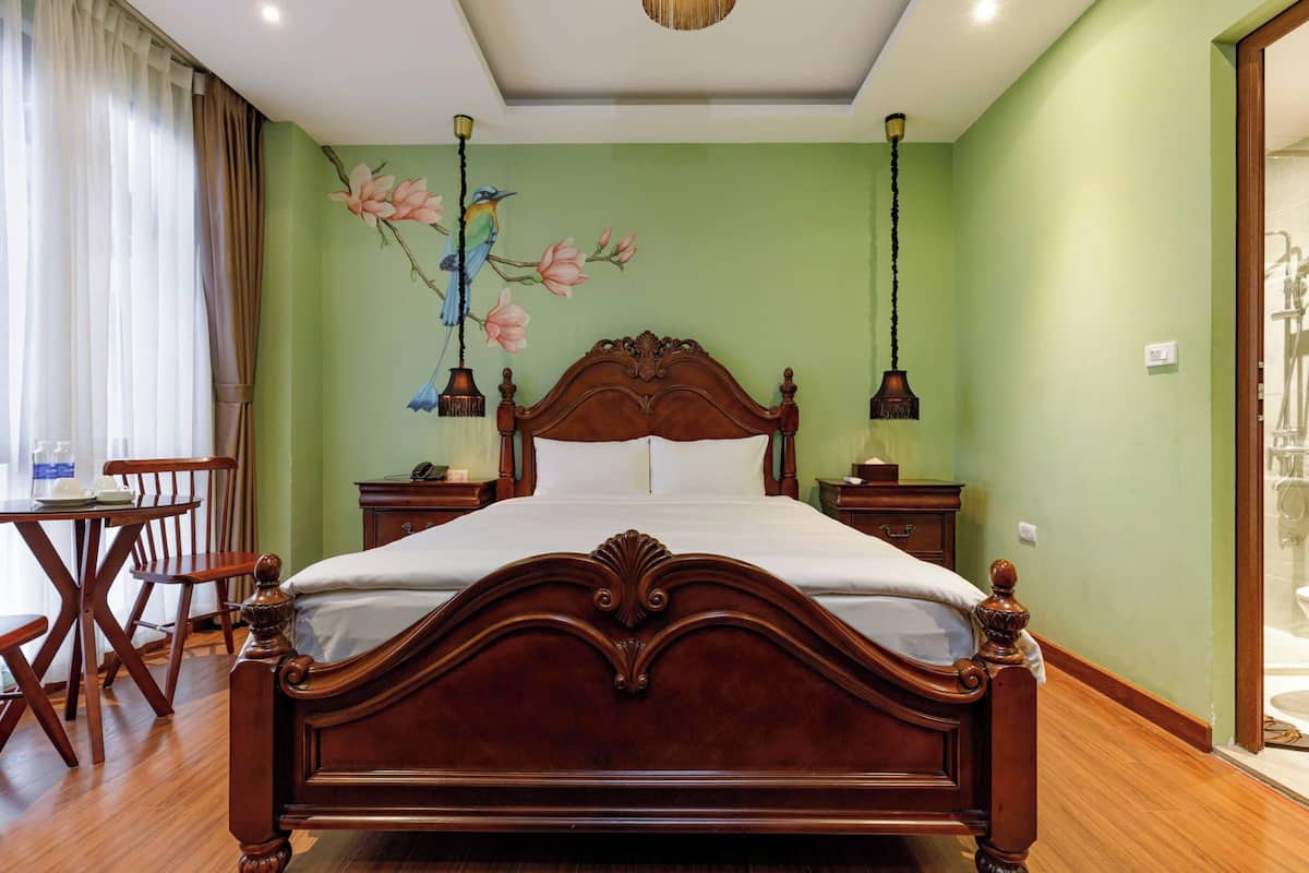 Quarto com cama de madeira, paredes verdes e um mural floral.