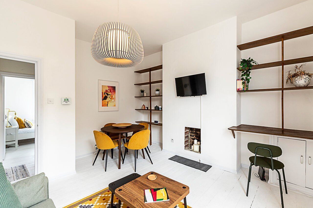 Uma sala de estar moderna com área de jantar, TV na parede e estante de livros.