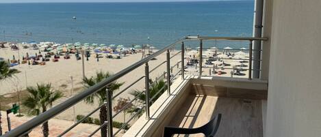 Uma varanda com vista para a praia, uma piscina e um corrimão.