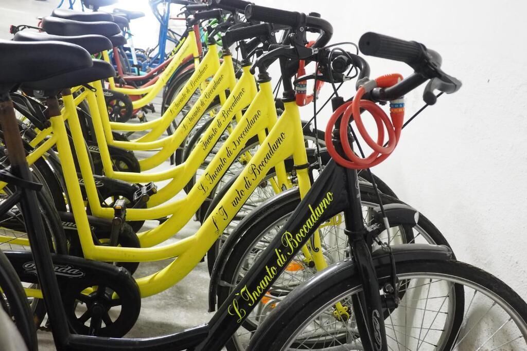 Uma fileira de bicicletas amarelas com a inscrição 'L'Incanto di Boccalanum' estacionadas em um espaço reservado.