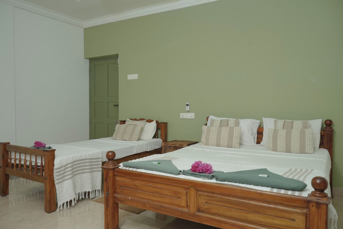 Um quarto com duas camas de madeira, um banco de madeira e uma porta verde.