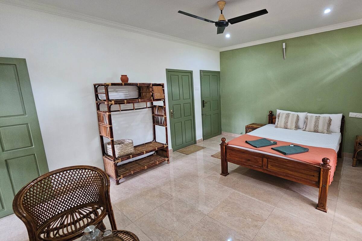 Quarto com cama de madeira, parede verde e ventilador de teto.