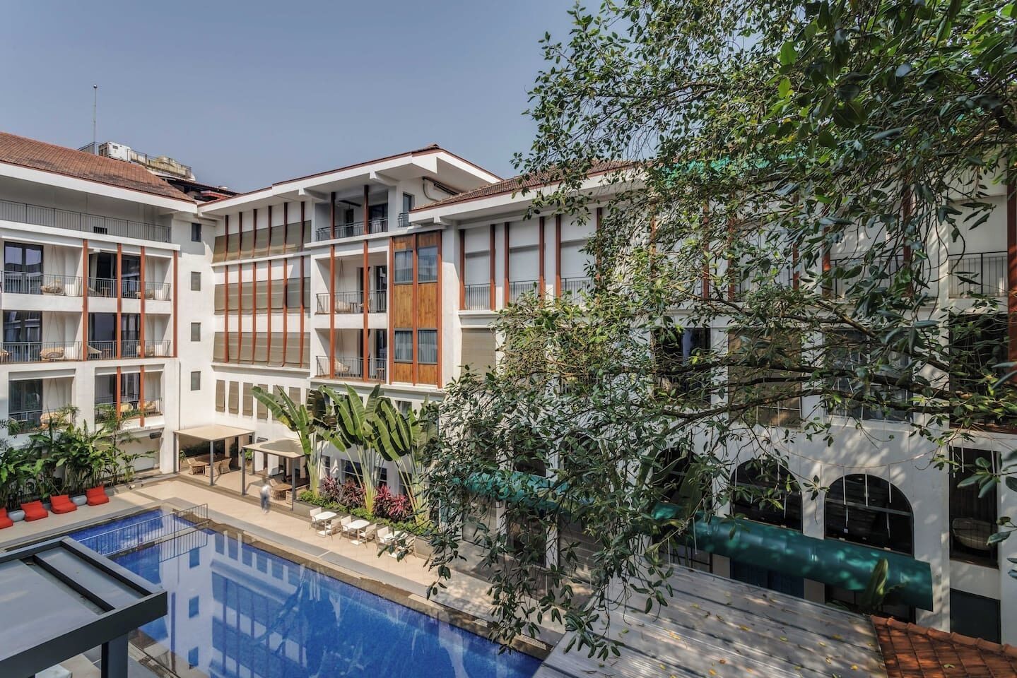 Um hotel moderno com várias varandas, piscina e vegetação exuberante.