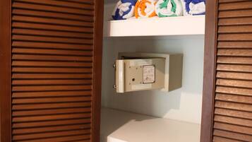 Um armário de madeira com portas de correr, uma prateleira com roupas dobradas e uma caixa de utilidades.