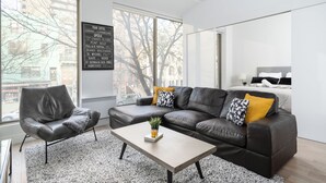 Uma sala de estar moderna com um sofá de couro, uma mesa de centro e uma janela grande com vista para a cidade.