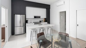 Uma cozinha moderna com uma ilha central, eletrodomésticos de aço inoxidável e banquetas.