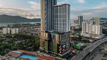 Um hotel moderno em arranha-céu, com design vertical marcante, várias varandas e piscina no terraço.