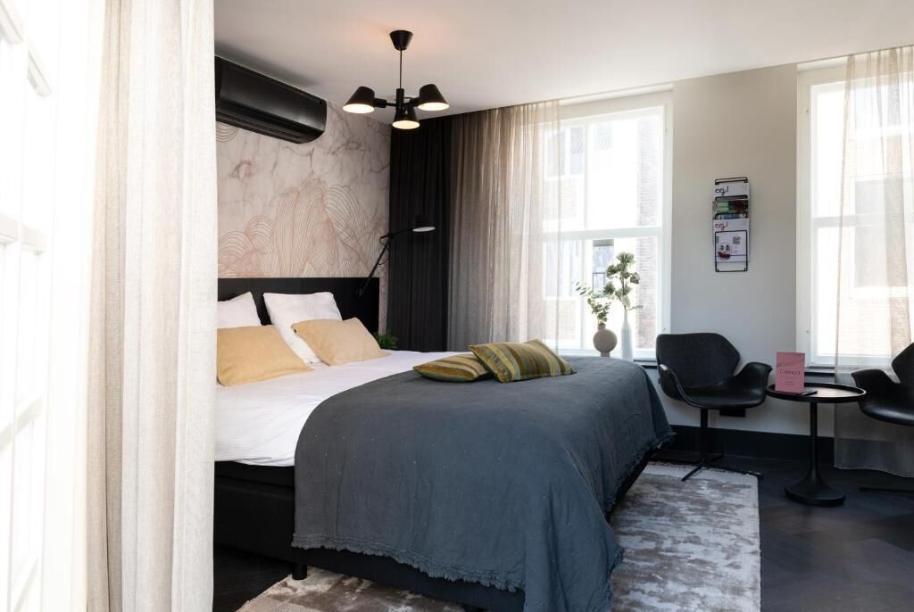 Quarto de hotel moderno com uma cama grande, uma escrivaninha e uma cadeira.