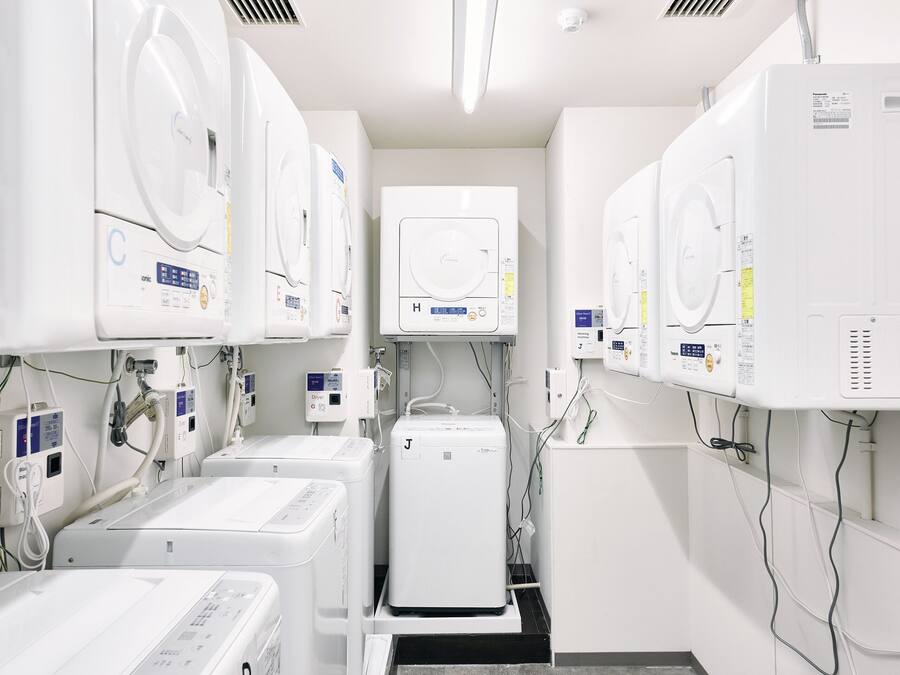 Uma lavanderia com várias máquinas de lavar e secar, dispostas em linha.