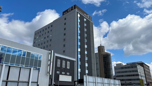 Um hotel moderno com uma placa grande que diz 'HOTEL', vários andares e uma torre cilíndrica.
