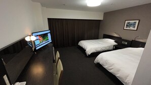 Quarto de hotel com duas camas, uma televisão em móvel, escrivaninha com telefone e quadro na parede.
